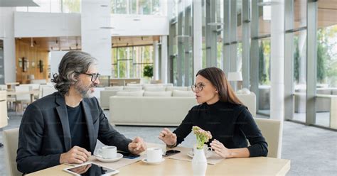 스마트 캐주얼웨어와 안경을 쓴 자신감 넘치는 두 동료가 커피 한 잔을 마시며 회사의 재무 뉴스나 프로젝트에 대해 논의하고 있다 사진 Unsplash의 사무실 이미지