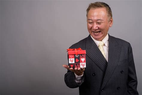 스튜디오 촬영의 성숙 회색 배경 발렌타인 준비 선물 상자를 들고 아시아 사업가 50 54세에 대한 스톡 사진 및 기타 이미지 50 54세 50 59세 기업 재무와