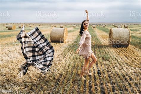 드레스와 따뜻한 격자 무늬와 아름다운 갈색 머리의 전체 길이 초상화 건초 베일과 밀 밭에서 산책을 즐기는 여자 갈색 머리에 대한
