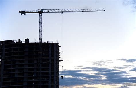 일몰에 작동하는 타워 크레인의 실루엣 콘크리트 양동이를 어푸작업에 부어 넣을 준비를 하고 있습니다 주거용 건물을 건설합니다 작은 선명도 가능한 세분성 0명에 대한 스톡 사진