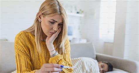 집에서 어머니와 아픈 아이의 체온을 측정합니다 침대에 앉아 아픈 어린 소년 소년은 머리가 아프고 열이 있습니다 어머니는 소년을 위로하고 있습니다 사진