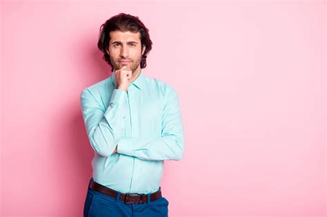 빈 공간이있는 파스텔 핑크 컬러 배경에 고립 된 손가락으로 얼굴 턱을 만지는 사려 깊은 남자의 사진 초상화 갈색 머리에 대한