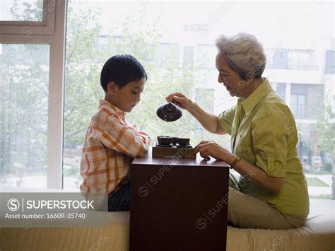 Grandmother And Grandson Sitting Cross Legged Drinking Tea Superstock
