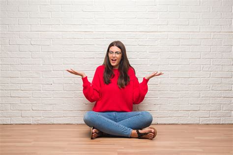 흰색 벽돌 벽 매우 행복 하 고 흥분 상자 식 큰 웃음과 비명과 손을 승리를 축 하 하는 바닥에 앉아 젊은 갈색 머리 여자 갈색