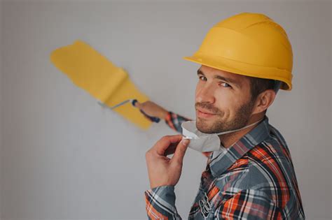 빌더는 건설 현장에서 작동 하 고 천장을 측정 합니다 주황색 헬멧과 페인트 롤러에 있는 일꾼은 벽을 칠합니다 가정의 방에 대한 스톡 사진 및 기타 이미지 Istock