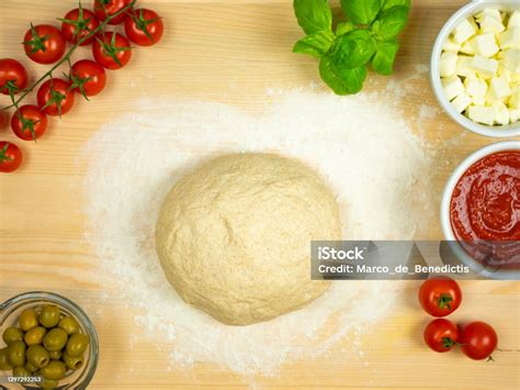 토마토 소스 체리 토마토 모짜렐라 바질 등 재료가 있는 피자 반죽 나무 테이블에 심장 모양의 밀가루 이탈리아 음식 피자를 만드세요 플랫 레이 맨 위 보기입니다 발렌타인 데이