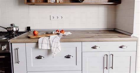 강철 오븐 냄비 야채 후추 향신료 나무 테이블 위에 기름을 곁들인 나무 도마에 칼이 있는 현대적인 주방에서 음식을 요리합니다 가정 음식 그레이 색상의 세련된