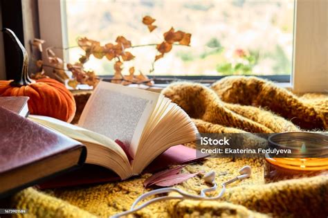 가을 시즌의 오디오북 또는 팟캐스트 편트 격자 무늬에 헤드폰과 단풍이 있는 책을 학습과 교육의 개념으로 펼치고 온라인 코스 또는 아늑한 가을 분위기의 음악 앱을 펼칩니다