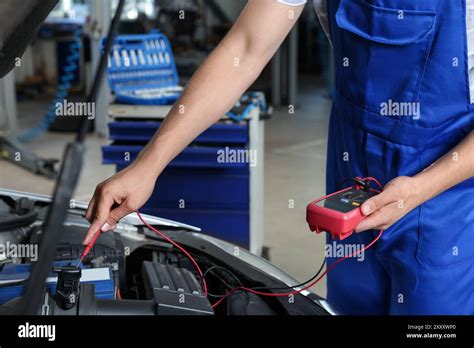Auto Mechanic With Multimeter Doing Diagnostic At Automobile Repair Shop Closeup Stock Photo