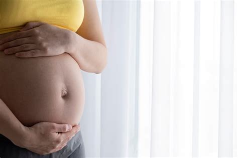 그녀의 알몸 임신 배를 손으로 만지는 여자 임신 시간에 아기 기대 관리 및 웰빙 프리미엄 사진