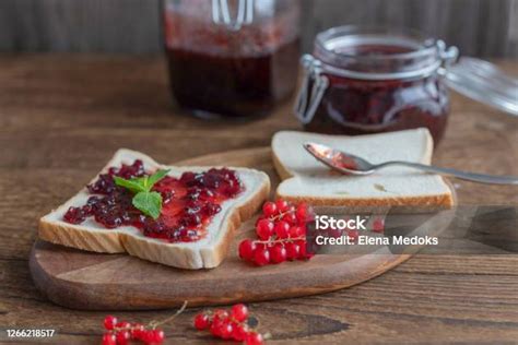 유리 항아리에 수제 빨간 건포도 잼과 나무 배경에 열매의 숫자 아침 식사로 마멀레이드를 곁들인 토스트 또는 빵 열매와 과일에서