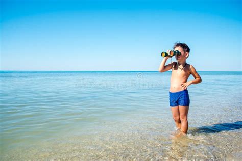 Мальчик смотрит через бинокли и видит море Стоковое Фото изображение насчитывающей военноморск