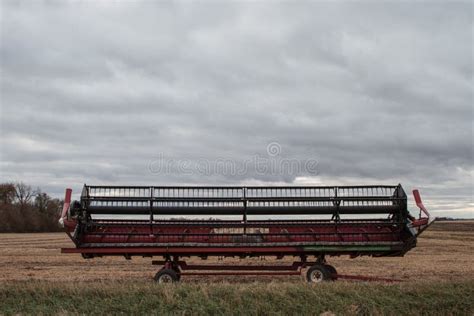 Combine Header In The Field Against The Background Of The Cloudy Sky