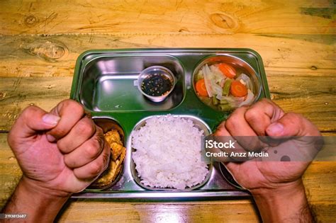 밥 프라이드 치킨 야채 소스가 담긴 스테인리스 스틸 런치 트레이에 포크와 숟가락을 교차시킨 손으로 밥 위에 교차시킨 모습은 영양가 있는 무료 점심을 상징합니다 강철에 대한