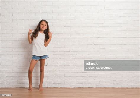 흰색 벽돌 벽 성공 기호 손으로 긍정적인 제스처를 하 고 이상 젊은 히스패닉 아이 Stading 엄지 웃 고 행복 쾌활 한 식 우승자 제스처와 카메라를 보면 가득 찬에 대한