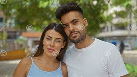 Couple Posing Outdoors In An Urban Park With Trees And Buildings In The