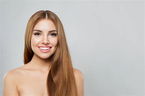 회색 배경에 긴 머리와 신선한 깨끗한 피부 스튜디오 초상화를 가진 매력적인 여자 자연스러운 화장품과 귀여운 미소를 가진 여성 모델의 아름다운 얼굴 20 24세에 대한 스톡