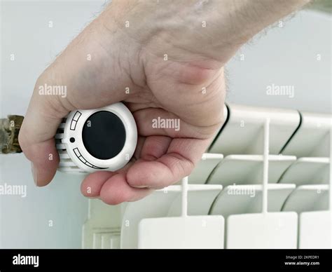 Closeup Of Male Hand Reducing Central Heating Radiator Temperature In
