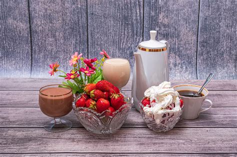 찻주전자 안경 음료와 잘 익은 딸기로 가득 찬 꽃병이 나무 테이블 위에 서 있습니다 긍정적 인 감정을 가진 정물 0명에 대한