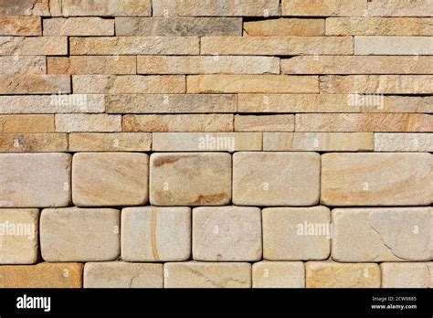 The Background And Texture Of A Wall Composed Of Hewn Rounded Yellow