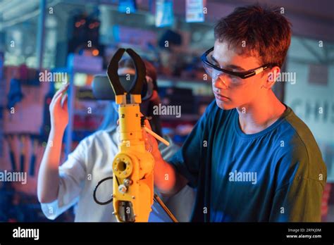 Teens Doing Experiments In Robotics In A Laboratory Boy In Protective