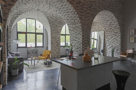 밝은 악센트가있는 중세 성 스타일의 아치가있는 잔인한 아파트 인테리어의 현대적인 고급 디자인 무료 레이아웃 주방 공간 좌석 및 식사 공간 아치 건축적 특징에 대한 스톡 사진