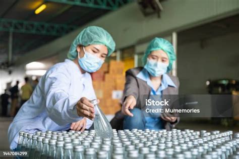 아시아 검사관 감독관 여성은 가공 공장의 창고에서 과일 음료 포장의 재고 제품을 확인하는 멸균 정장을 입은 보조 직원을 가지고 있습니다 식품 가공 공장에 대한 스톡 사진 및