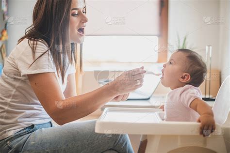 母亲用汤匙喂她的小女儿