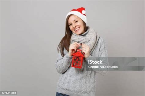 예쁜 회색 스웨터에 산타 소녀 크리스마스 모자 회색 배경에 고립 된 빈티지 랜 턴 촛대를 들고 스카프 행복 한 새 해 2019