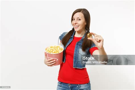 영화 영화를 보고 팝콘 그리고 Bitcoin 흰색 배경에 고립의 양동이 들고 캐주얼 옷에 젊은 미소 매력적인 갈색 머리 여자의 초상화 영화 개념에서의 감정