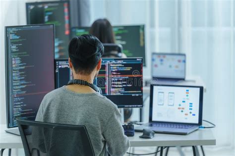 asian software developers working on multiple screens displaying code