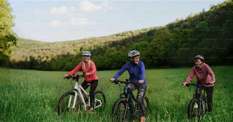 행복한 활동적인 노인 여성 친구들은 초원의 자연 속에서 야외에서 함께 자전거를 타고 있습니다 행복한 활동적인 노인 여성 친구들은 초원의 자연 속에서 야외에서 함께 자전거를