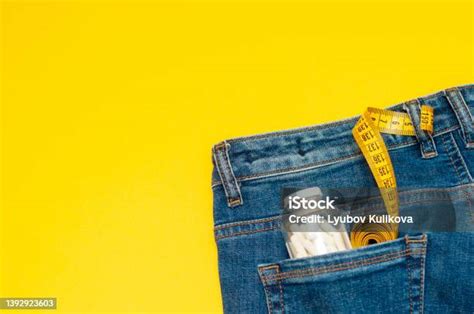 노란색 측정 테이프와 알약이있는 유리 항아리는 노란색 배경의 파란색 청바지 뒷주머니에 있으며 공간을 복사합니다 0명에 대한 스톡 사진 및 기타 이미지 Istock