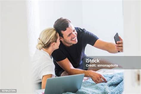 아름 다운 젊은 천년 백인 부부 기술 촬영 Selfie 스마트폰 웃 고 데 재미와 함께소셜 미디어와 웹 공유침대에서 노는 사랑 및 라이프 스타일 개념 2명에 대한 스톡 사진