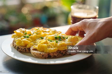 아침에 건강한 아침 식사를 즐기면서 스크램블 에그를 얹은 구운 빵 한 조각을 들고 있는 여성의 손이 잘린 이미지 달걀에 대한 스톡 사진 및 기타 이미지 Istock