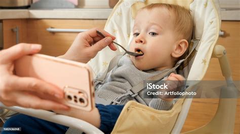 유아용 의자에서 죽을 먹고 스마트폰으로 만화를 보는 귀여운 소년의 초상화 아이에 대한 스톡 사진 및 기타 이미지 아이 장치 화면 중독 Istock
