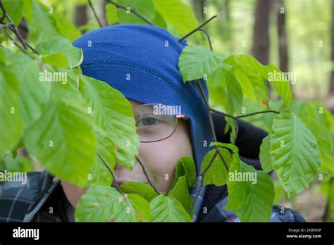 Boy Playing Hide And Seek In The Forest Boy Looks Through The Green