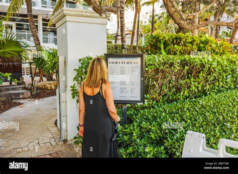 Woman In Black Dress Reading Dildo Beach Bar Menu At Entrance Surrounded By Green Tropical