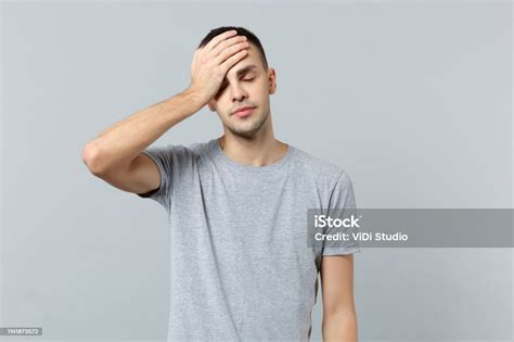 눈을 감고 캐주얼 옷에 피곤한 젊은 남자의 초상화 스튜디오에서 회색 벽 배경에 고립이 마에 손을 넣어 사람들은 진심으로 감정 라이프 스타일 개념입니다 복사 공간을 모의