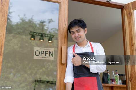 사업주는 고객을 환영 할 준비가되었음을 보여주기 위해 엄지 손가락을 치켜 올립니다 웨이트리스 남자는 현대 카페 커피 숍에서