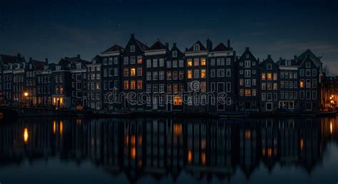 Row Of Illuminated Historic Buildings Reflected In A Dark Canal At