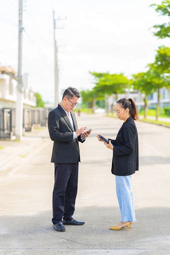 양복을 입은 꽃미남 부동산 사업가가 공사 중 집 앞에 서서 태블릿을 사용하여 건축주와 약속을 잡는 모습 세로 이미지 2명에 대한 스톡 사진 및 기타 이미지 Istock
