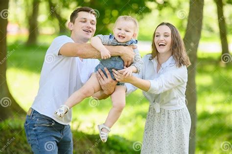 счастливая мама папа веселится в парке пока гуляет держа свою дочь бросает ее Стоковое