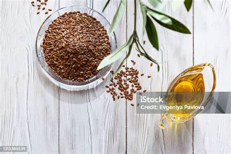 아마씨 오일과 흰색 나무 테이블에 아마 씨앗의 무리 오일과 아마씨 올리브 가지 및 복사 공간이있는 현대 의 정물 유리 그릇 아마씨에 대한 스톡 사진 및 기타 이미지 Istock