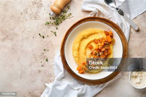 가벼운 콘크리트 배경에 흰색 그릇에 버터 호박 마늘 짭짤한 파마산 치즈와 폴렌타 전통적인 베이직 이탈리안 푸드 비건 음식 맨 위 보기입니다 공간을 복사합니다 가루로 빻은에