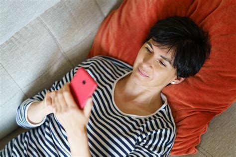 집에서 소파에 누워있는 스마트 폰에서 소셜 네트워크를 확인하는 여성 50 54세에 대한 스톡 사진 및 기타 이미지 50 54세 스마트폰 여자 Istock