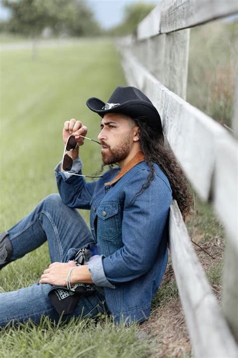 울타리 옆에서 휴식을 취하는 거친 남자 · 무료 스톡 사진