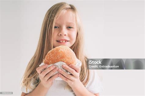 햄버거의 조각을 들고 하는 아이 아이 패스트 푸드를 먹는다 도움이 안 음식 매우 배고픈 아기입니다 흰색 배경에 고립 된