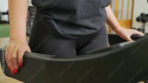 A Babe Woman In Tight Black Sportswear In The Process Of Training On A Treadmill Holding Hands