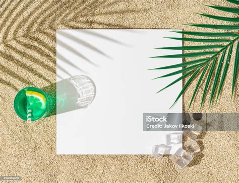 레몬 슬라이스 야자수 잎 얼음 조각 열대 잎 그림자 및 해변 모래 배경에 종이 카드 메모 복사 공간을 가진 녹색 상쾌한 음료의 창조적 인 레이아웃 미니멀한 이국적인 여름